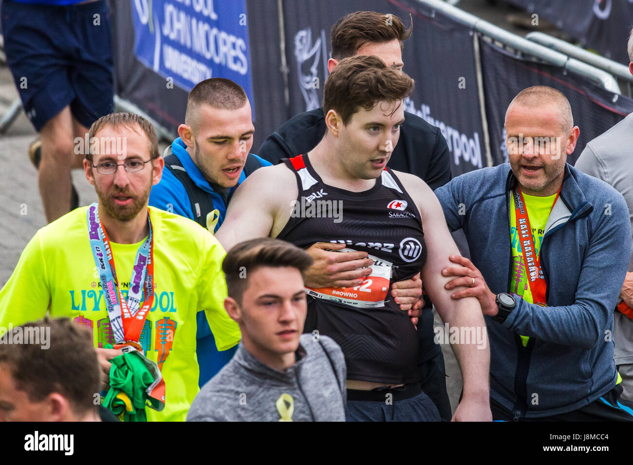 A male runner gains assistance after struggling over the finishing line ...