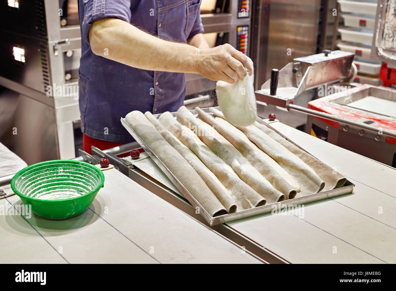 Baker pours flour on bread loaves before baking at a bakery Stock Photo ...