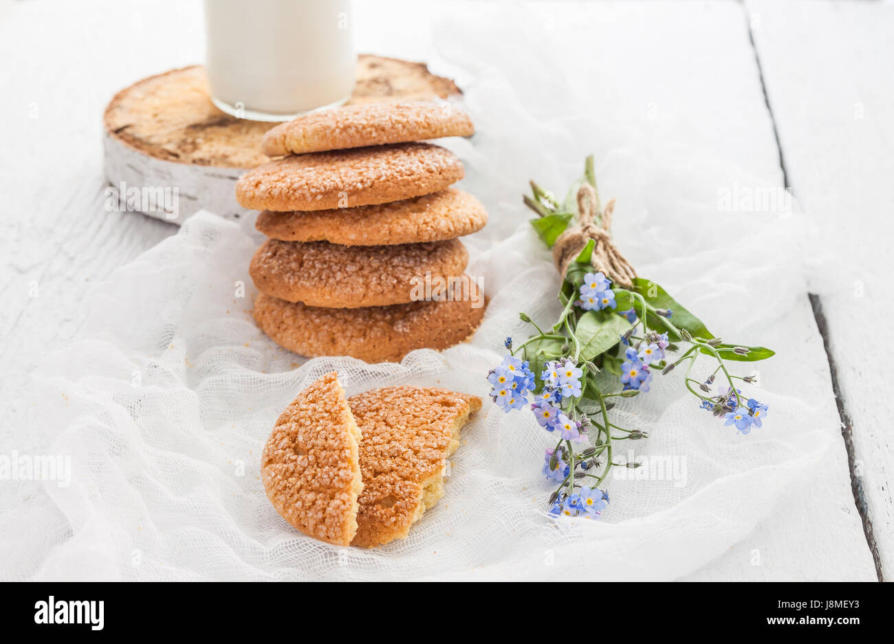 A stack of round shortbread cookies, a bottle of milk and a bouquet of ...