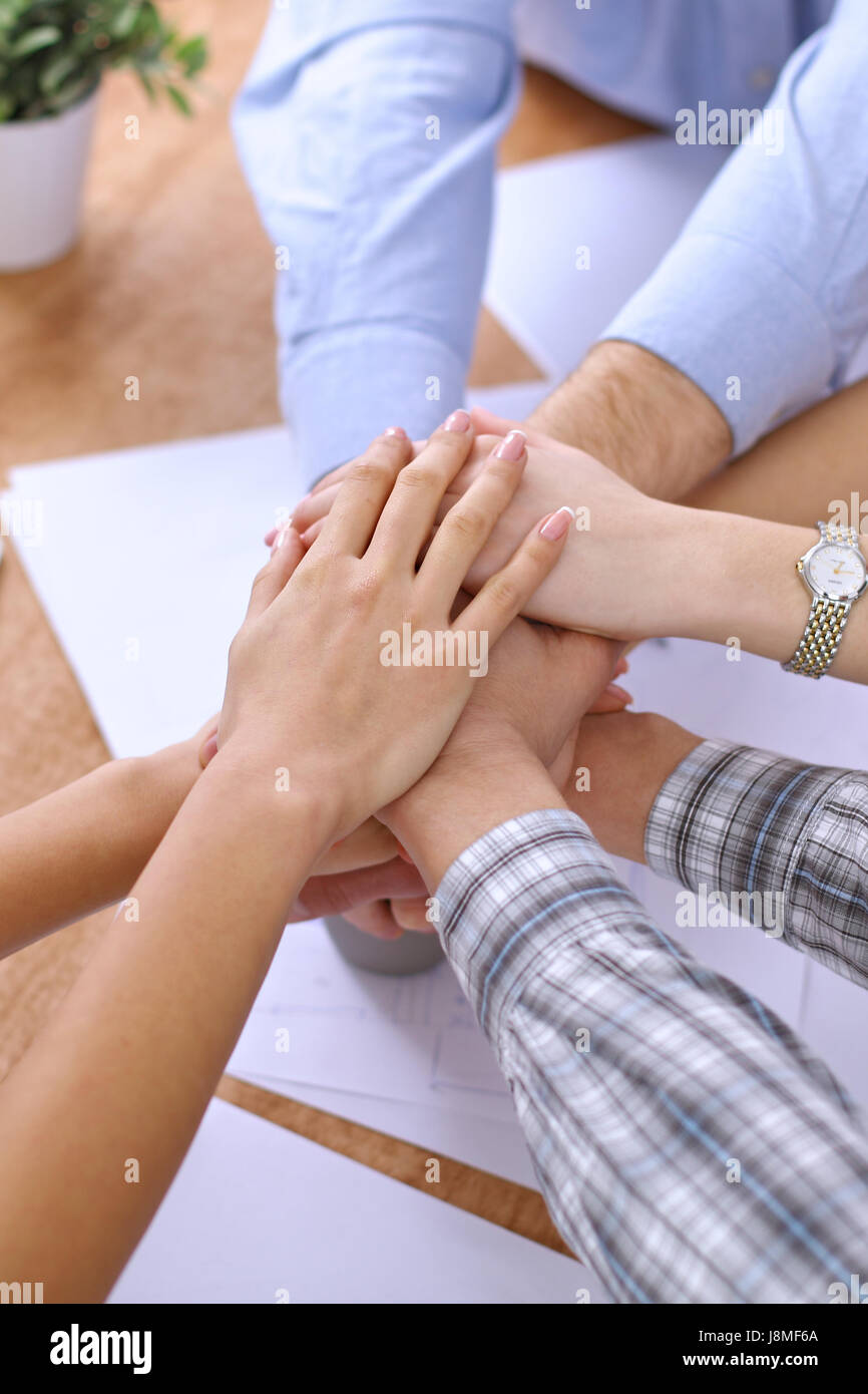 Business people joining hands over table Stock Photo - Alamy