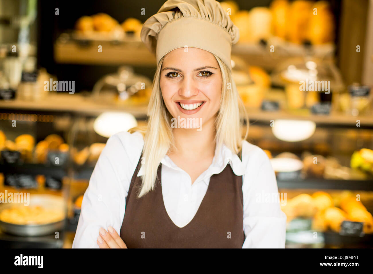 Beautiful young woman smiling confidently posing in her baker shop ...