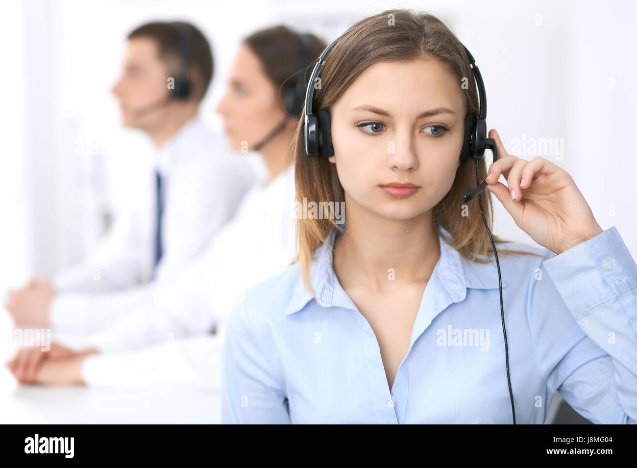 Call center operators. Focus at young beautiful business woman in headset Stock Photo - Alamy