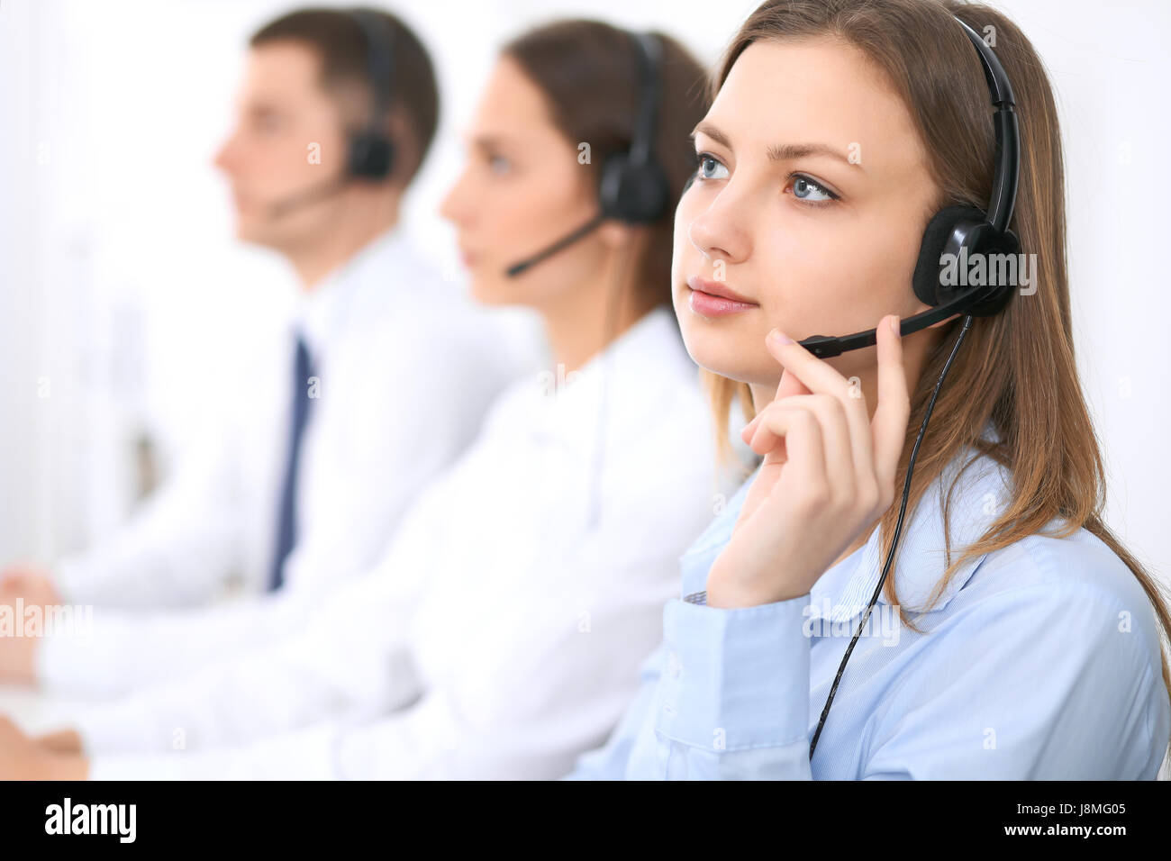 Call center operators. Focus at young beautiful business woman in headset Stock Photo - Alamy