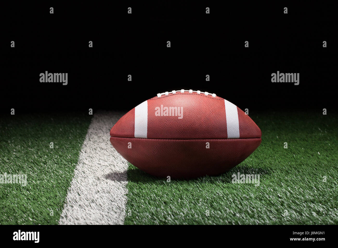 College style football on grass field and stripe at night low angle ...