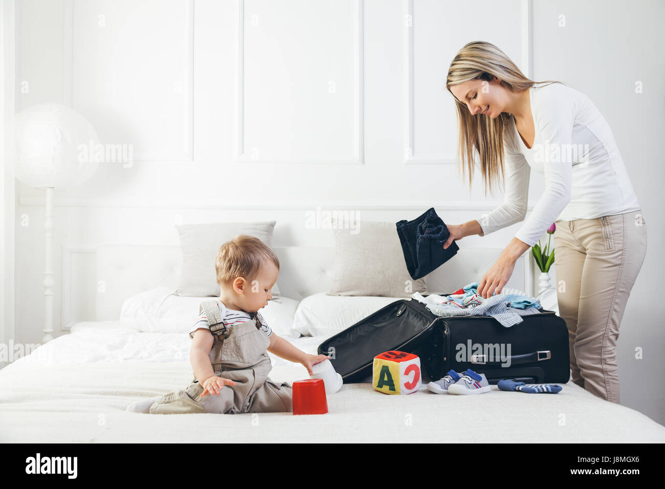 Travelling with kids. Happy mother with her child packing clothes for ...