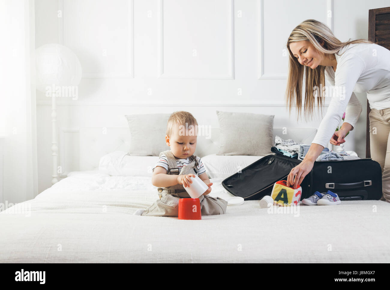 Travelling with kids. Happy mother with her child packing clothes for ...
