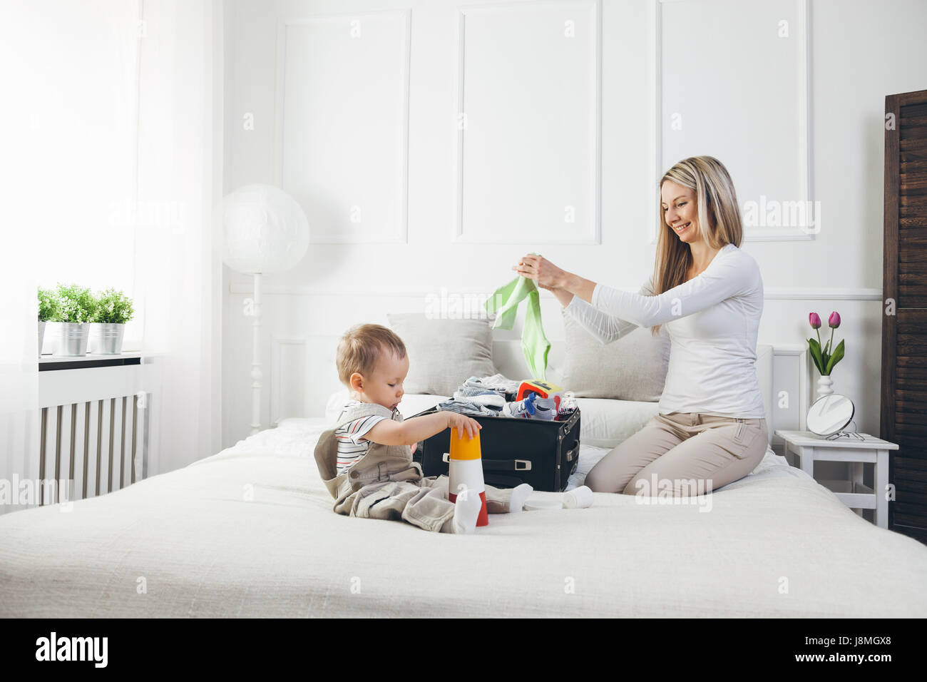 Travelling with kids. Happy mother with her child packing clothes for ...