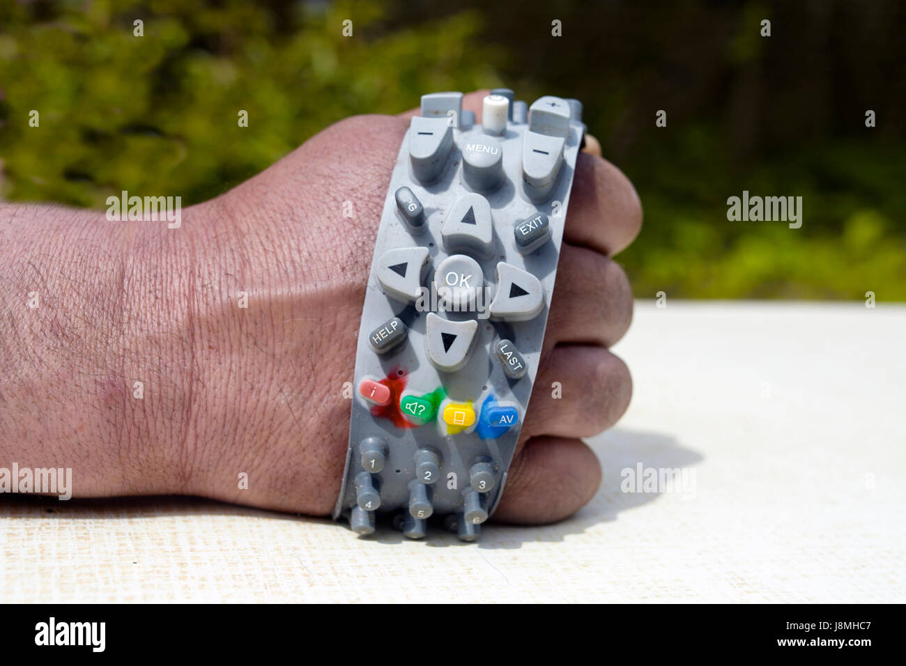 Male hand wrapped in rubber TV remote control, outdoor cropped shot ...