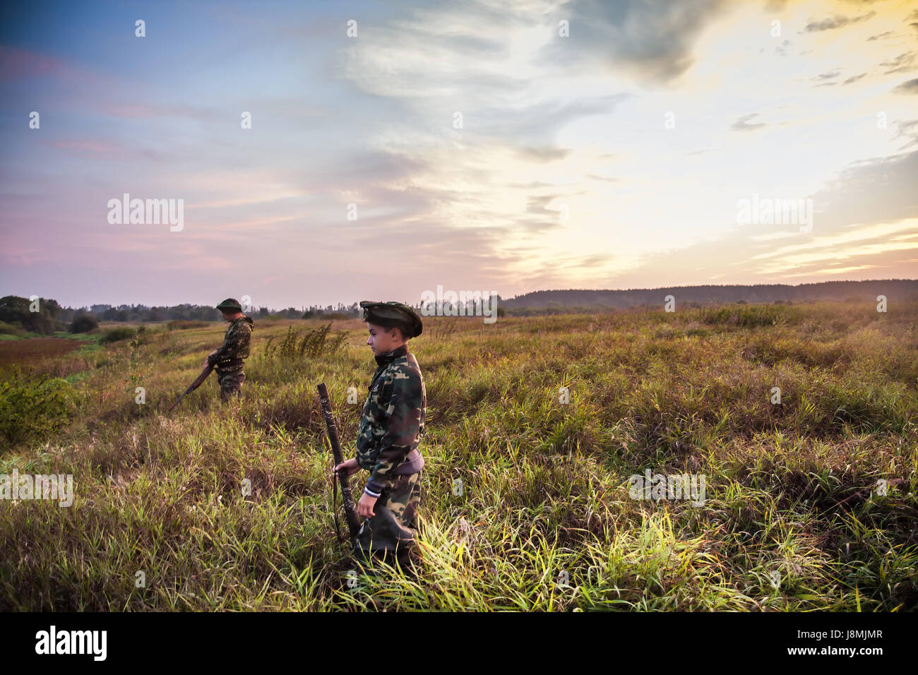 Hunters choosing good position for duck hunting in rural field during ...