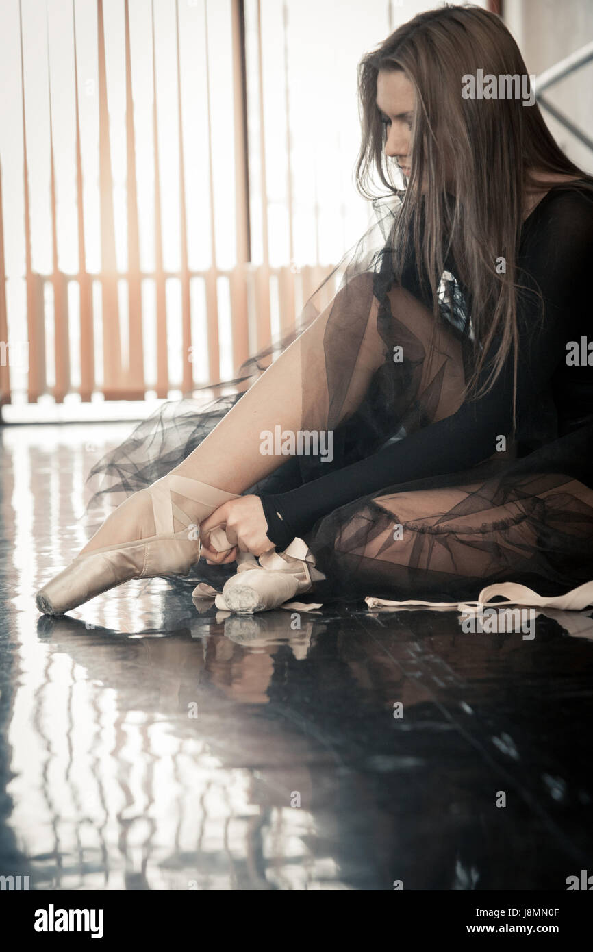 Female ballet dancer sitting on a floor in a dancing class puttinf on ...