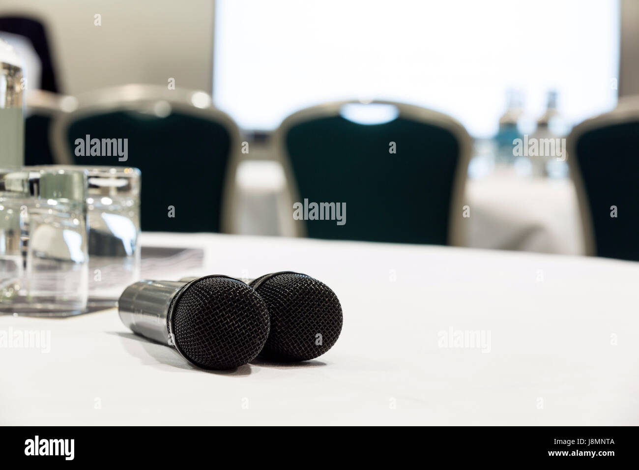 Two microphones on a white table used for Q&A at a conference or ...