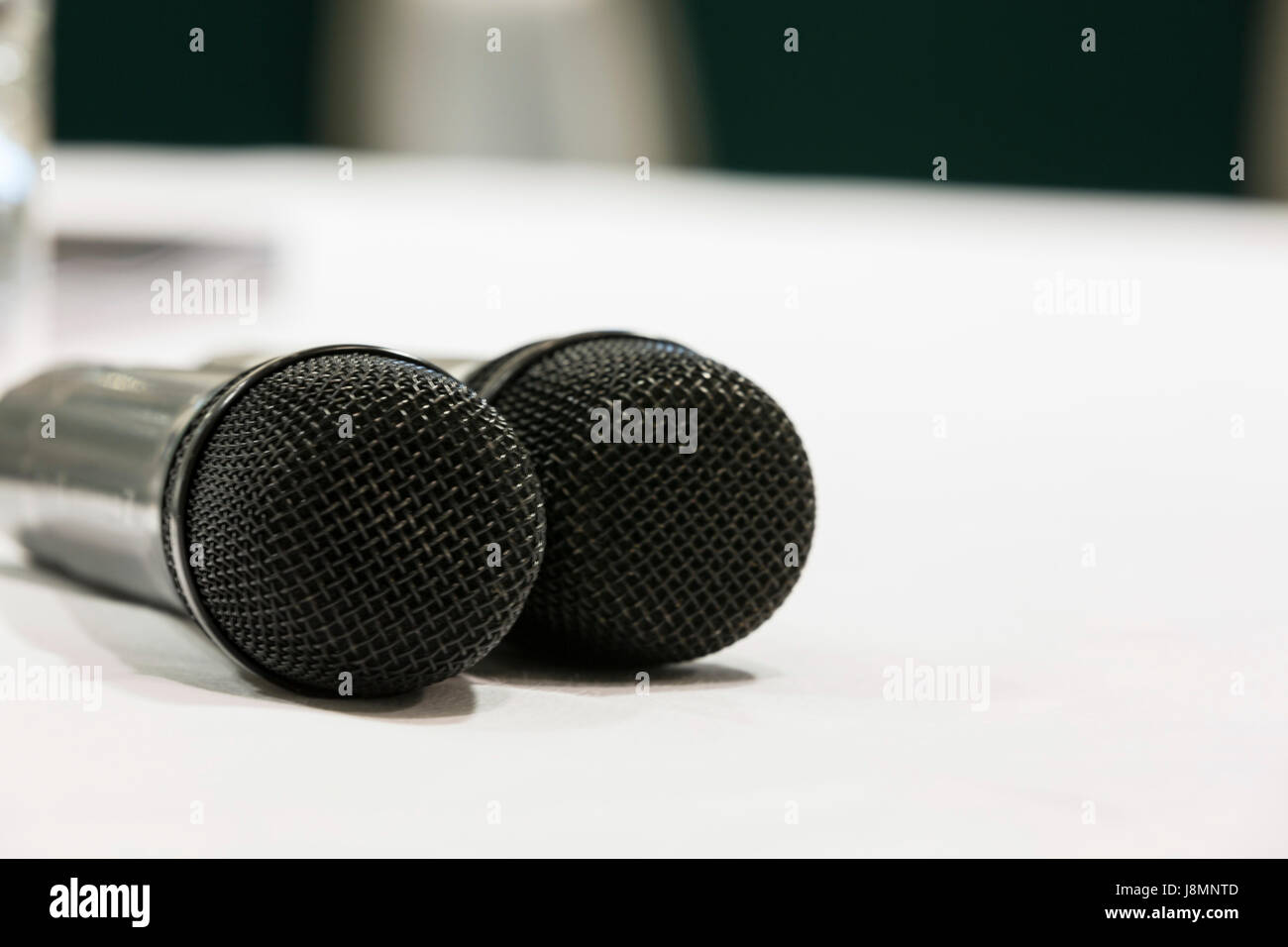 Two microphones on a white table used for Q&A at a conference or ...