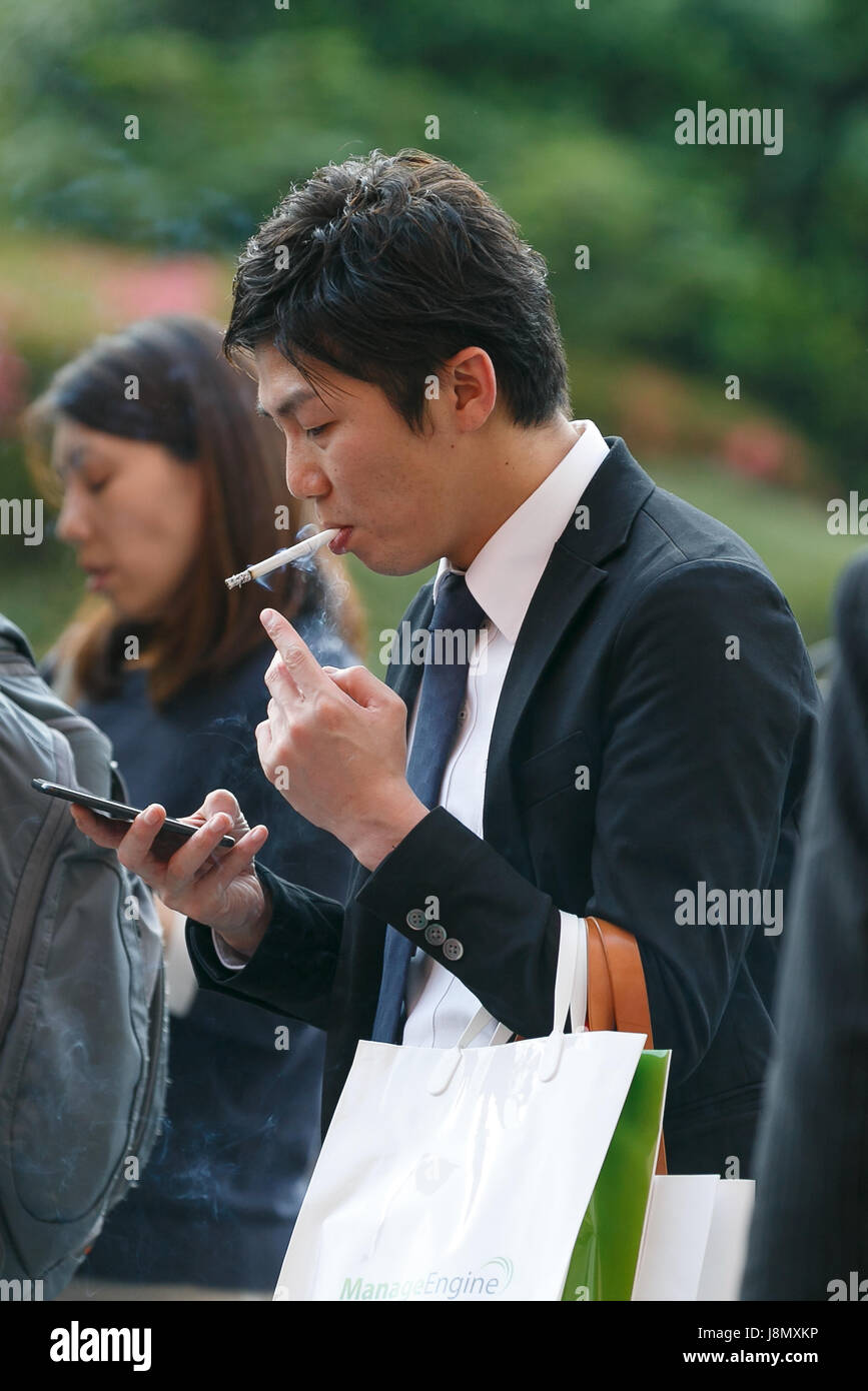 A man smokes in a designated smoking area outside Shinjuku Station on ...