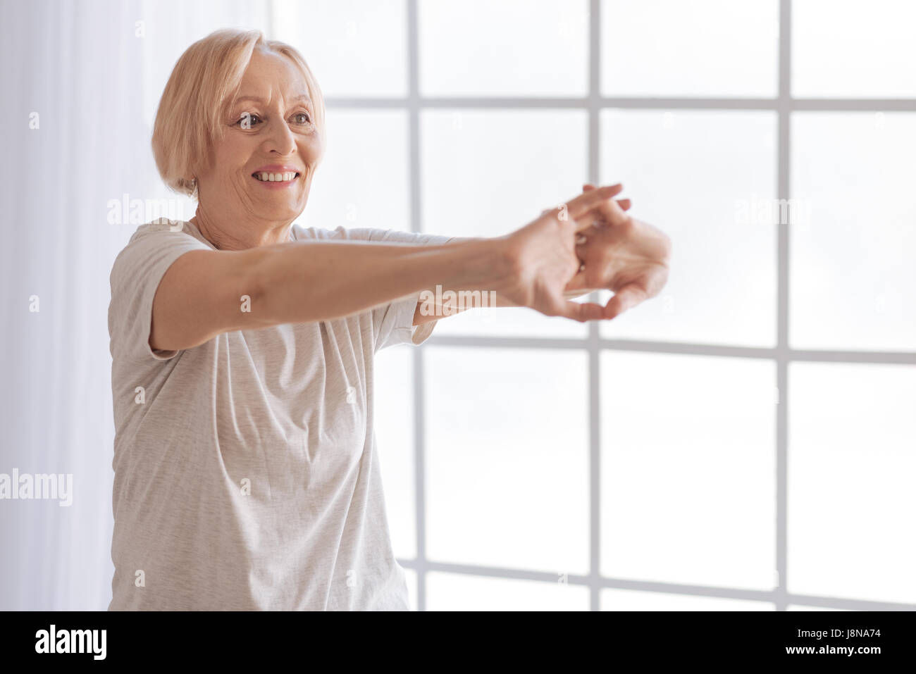 Morning exercises. Delighted female person stretching her arms looking ...