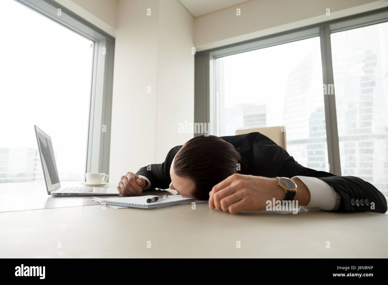 Exhausted businessman lying on his desk in office Stock Photo - Alamy