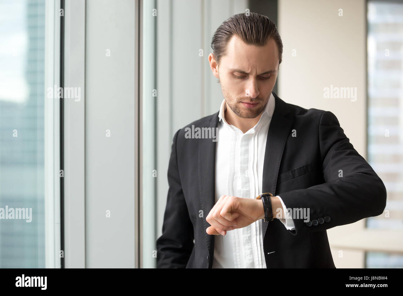 Busy businessman looking on wristwatch in office Stock Photo - Alamy