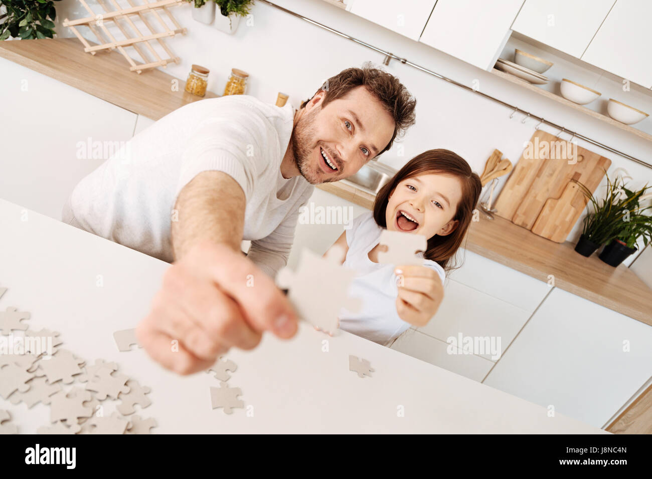 Love doing puzzles. Broadly smiling happy single-parent family looking ...