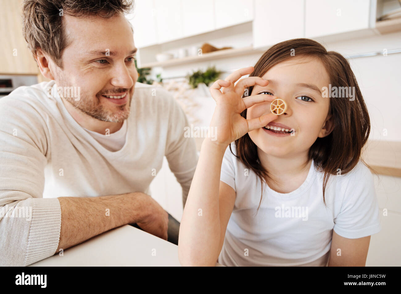 Fooling around. Cheerful cute girl goofing around by pressing a piece ...