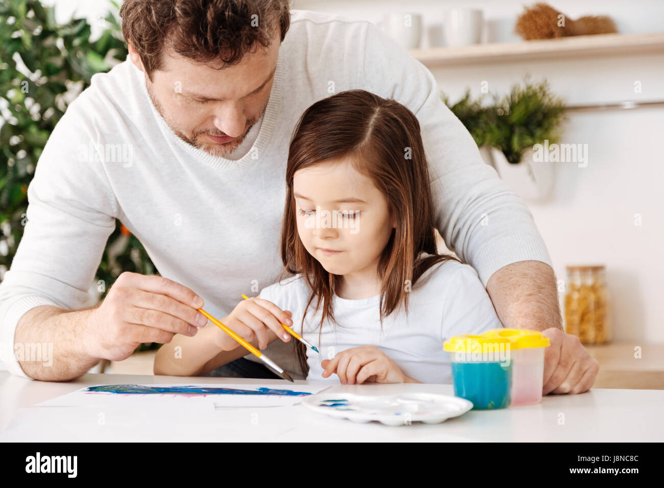 Best time. Gentle caring father helping his favourite daughter in painting a watercolour picture ...