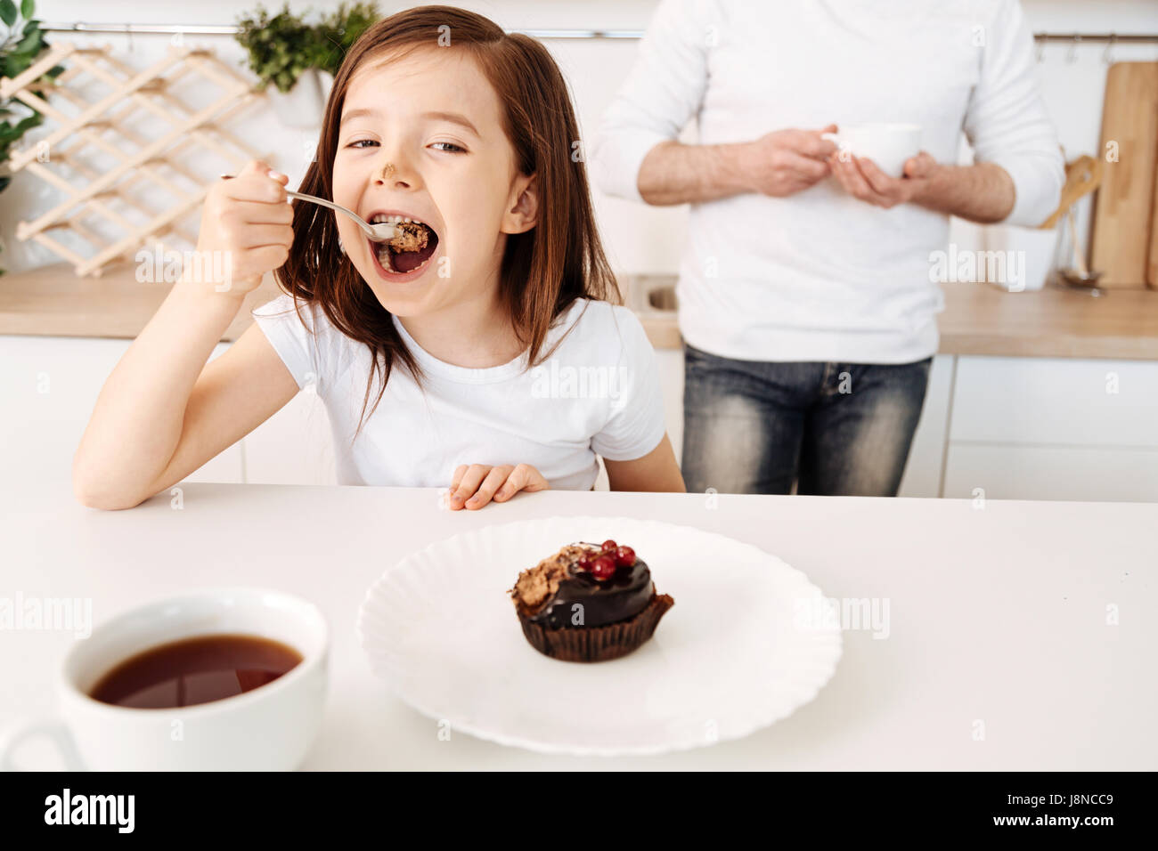 I love cake. Overjoyed little girl eating delicious cake so much that ...