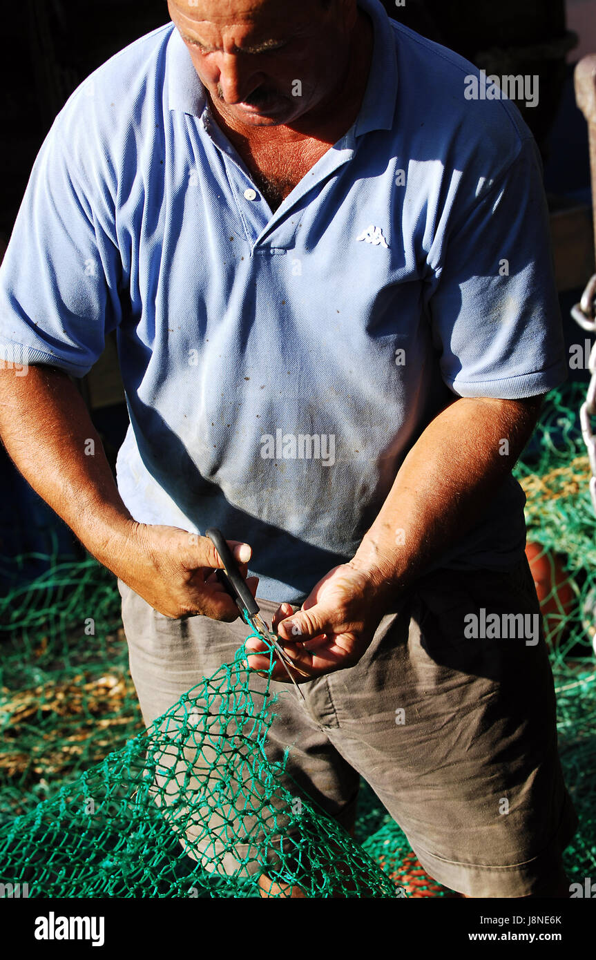 Fisherman mending his fishing net Stock Photo - Alamy