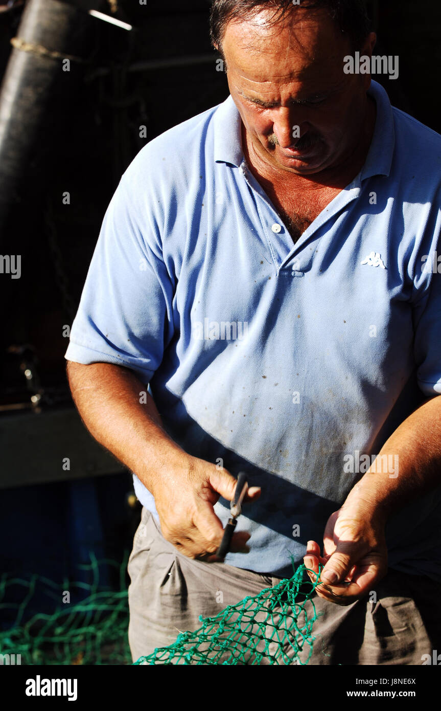 Fisherman mending his fishing net Stock Photo - Alamy