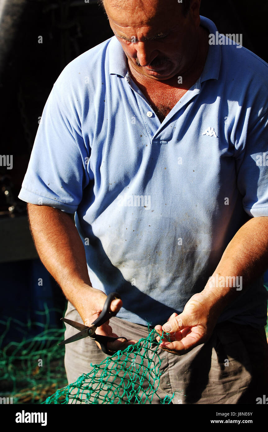 Fisherman mending his fishing net Stock Photo - Alamy