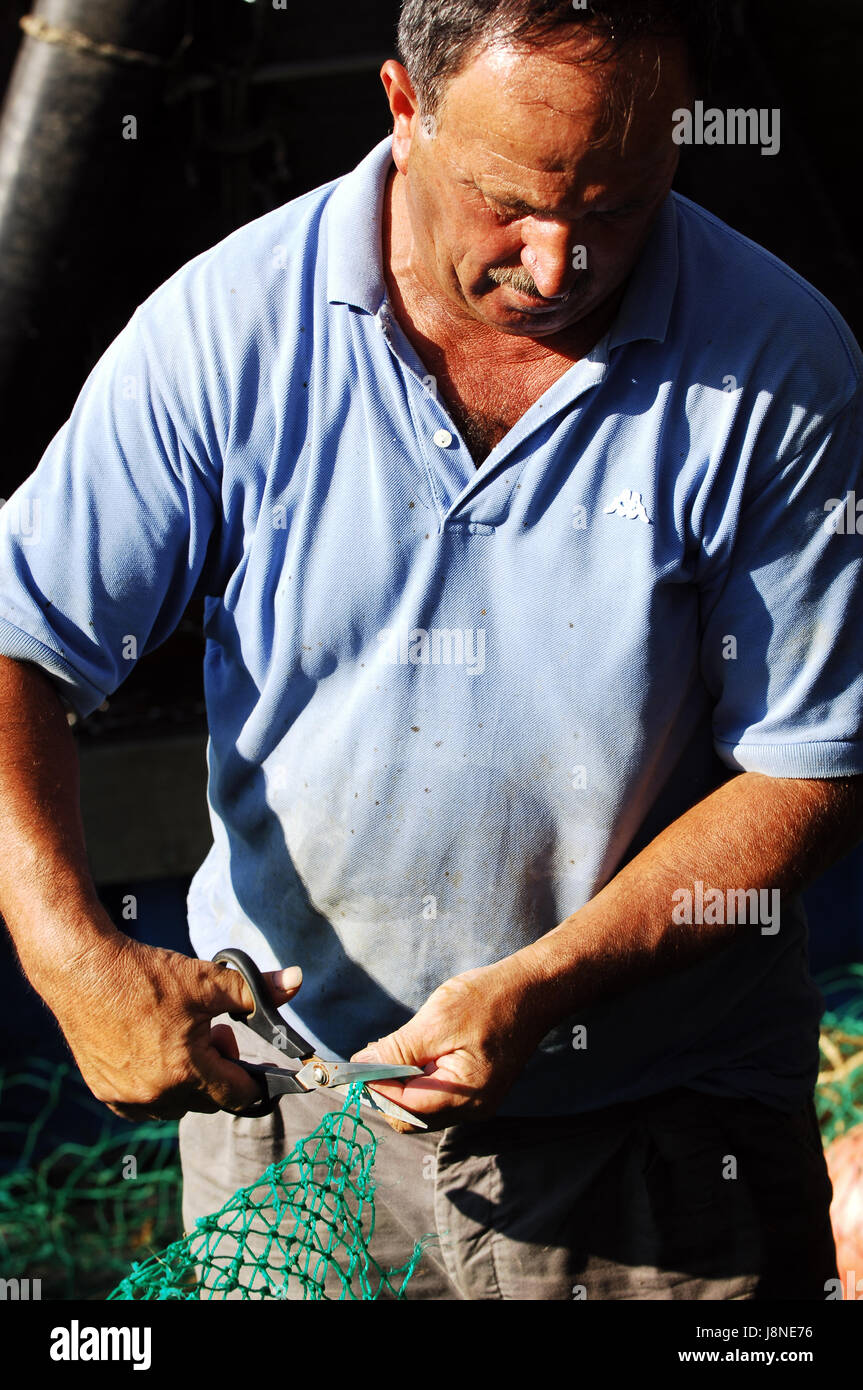 Fisherman mending his fishing net Stock Photo - Alamy