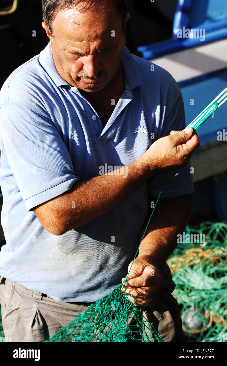 Fisherman mending his fishing net Stock Photo - Alamy