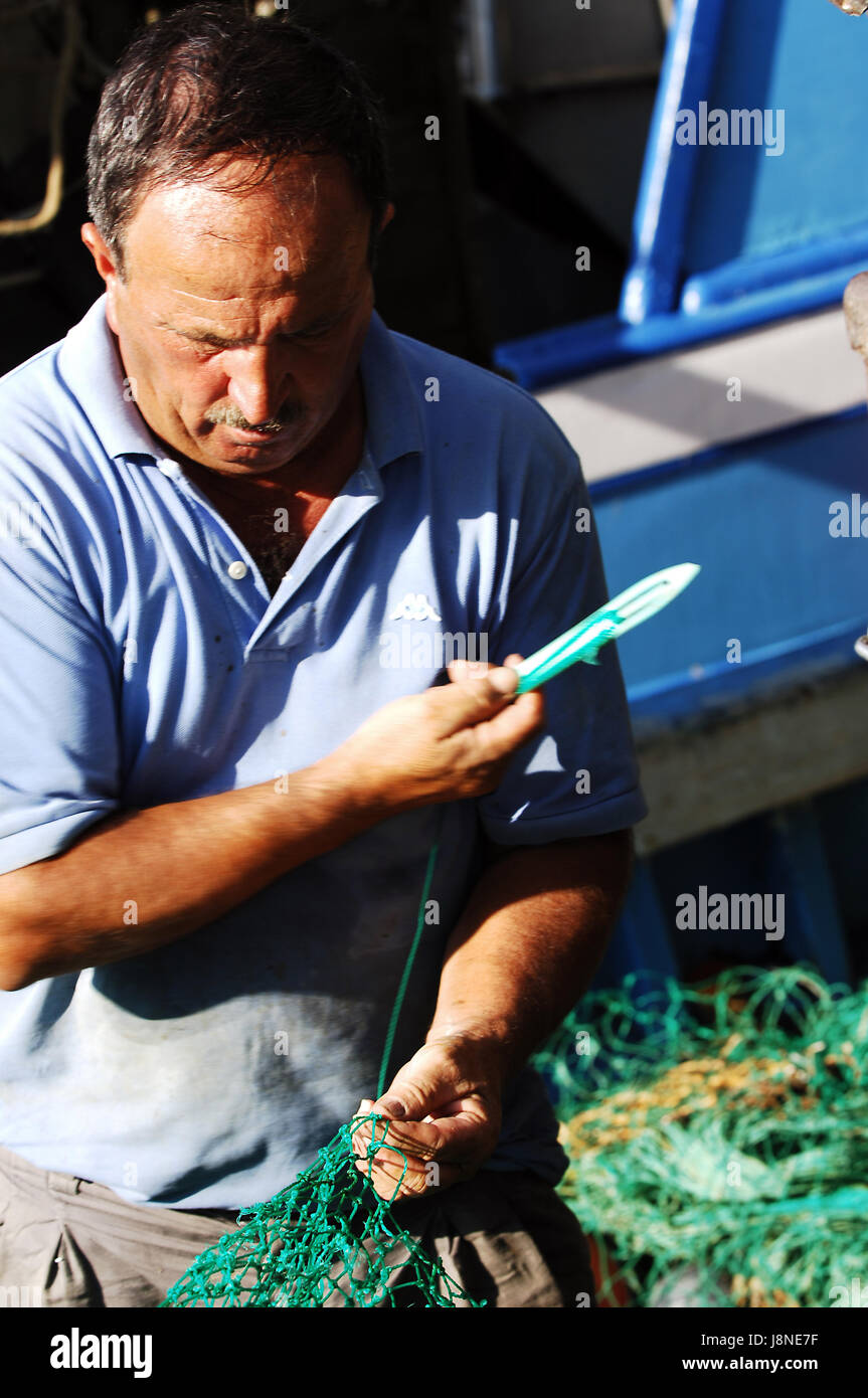 Fisherman mending his fishing net Stock Photo - Alamy