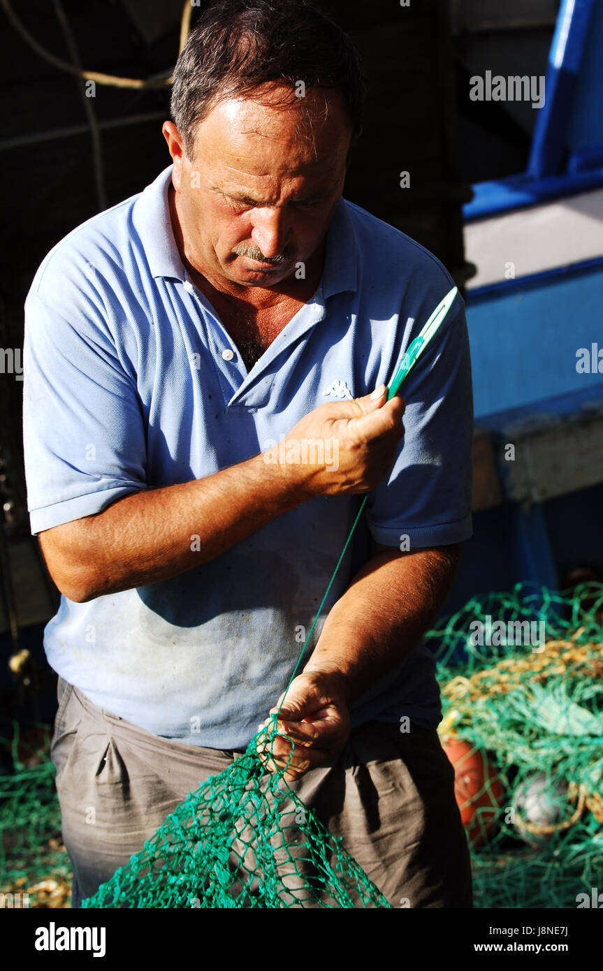 Fisherman mending his fishing net Stock Photo - Alamy