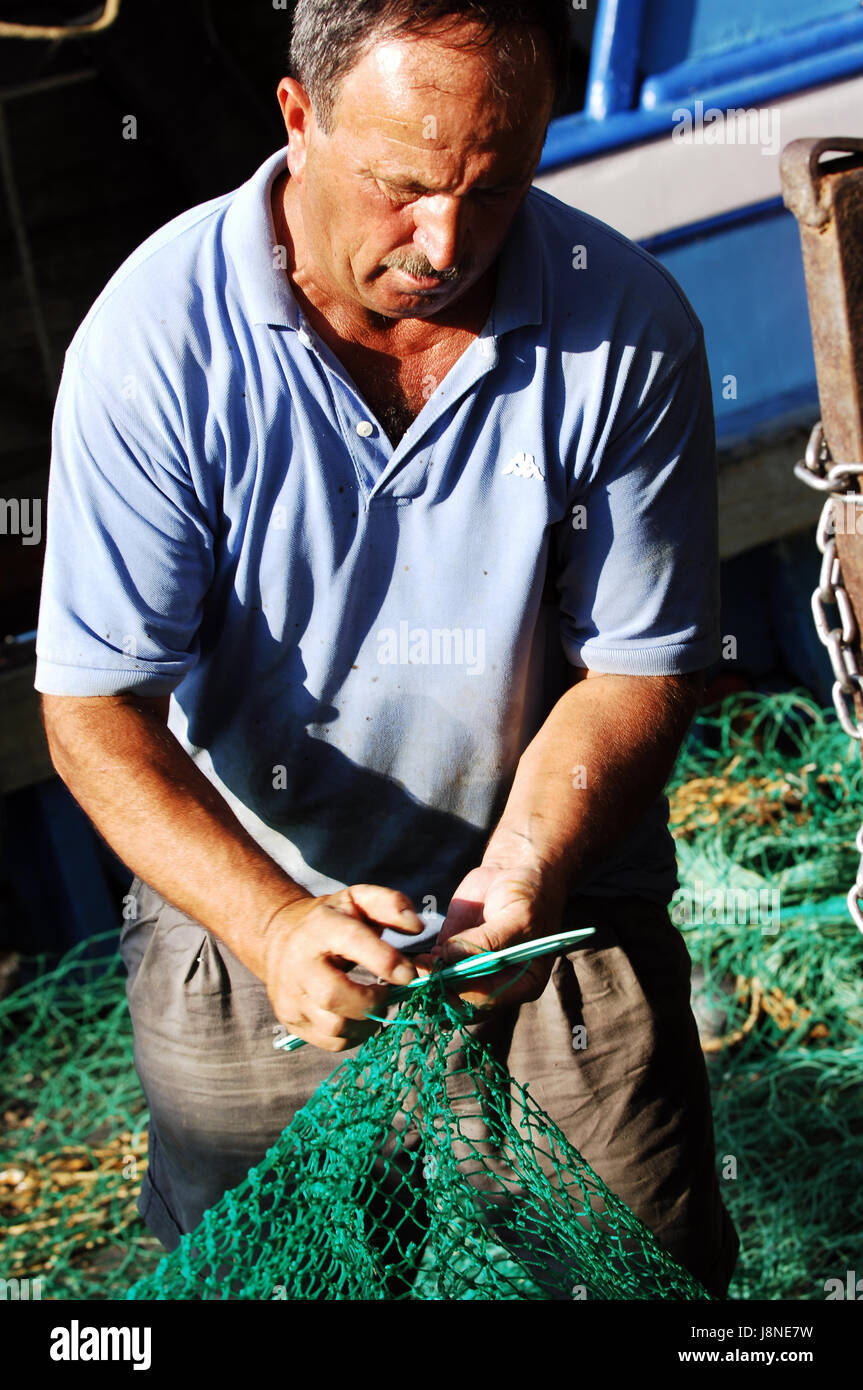 Fisherman mending his fishing net Stock Photo - Alamy