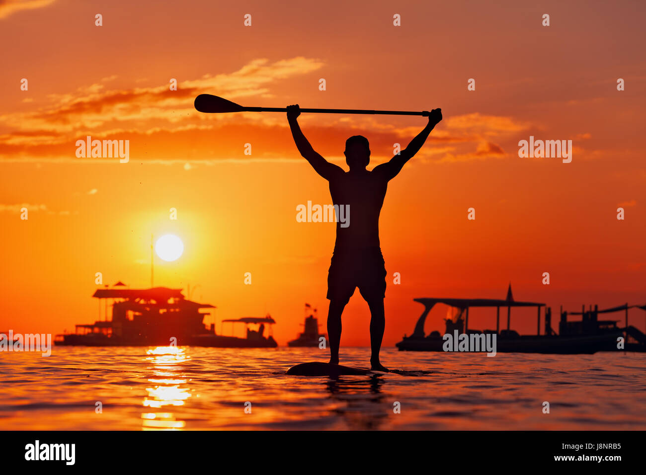 Active paddle boarder. Black sunset silhouette of young sportsman ...