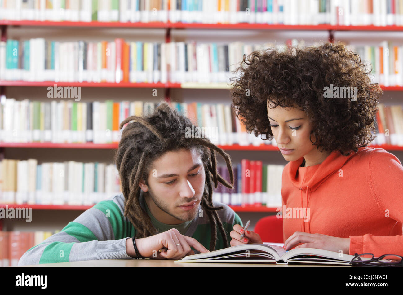 Two students learning together indoors in library Stock Photo - Alamy