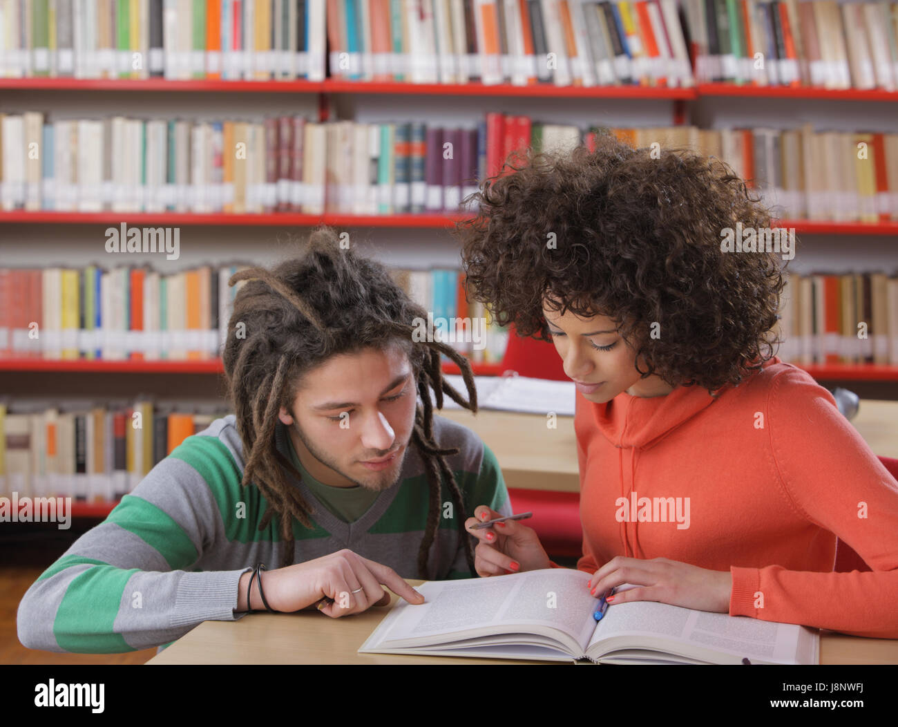 Two students learning together indoors in library Stock Photo - Alamy