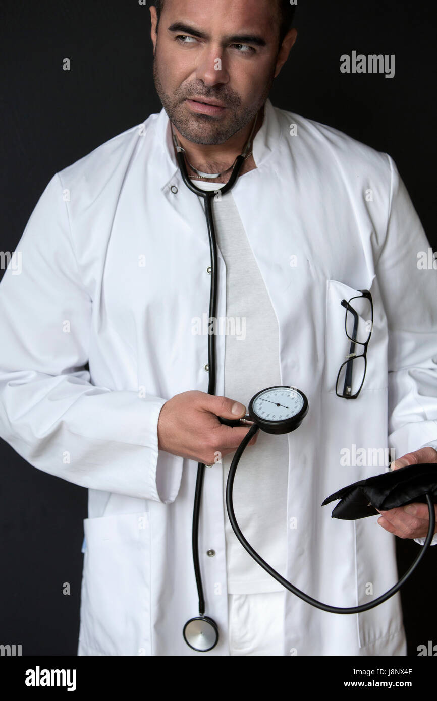 handsome doctor holding a sphygmomanometer and looking thoughtful Stock ...