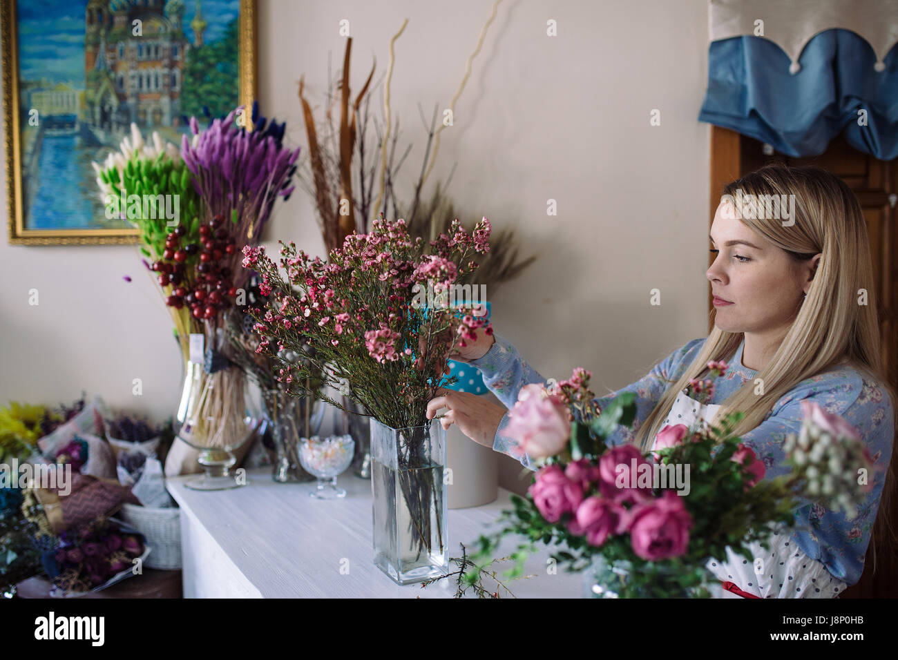 woman florist making bouquet of pink flowers indoor. Female florist ...