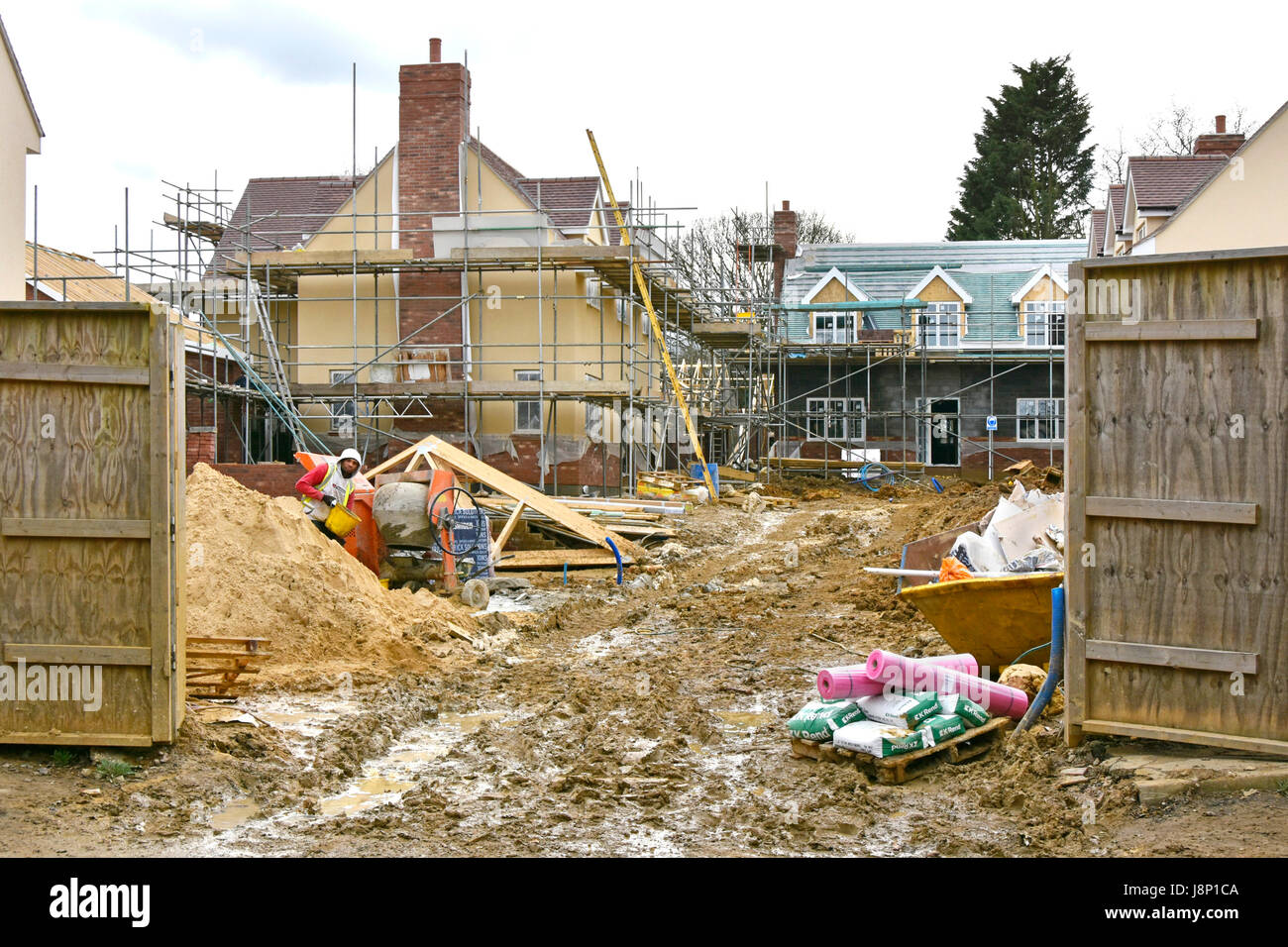 New home being erected in winter mud & clay on small congested house ...