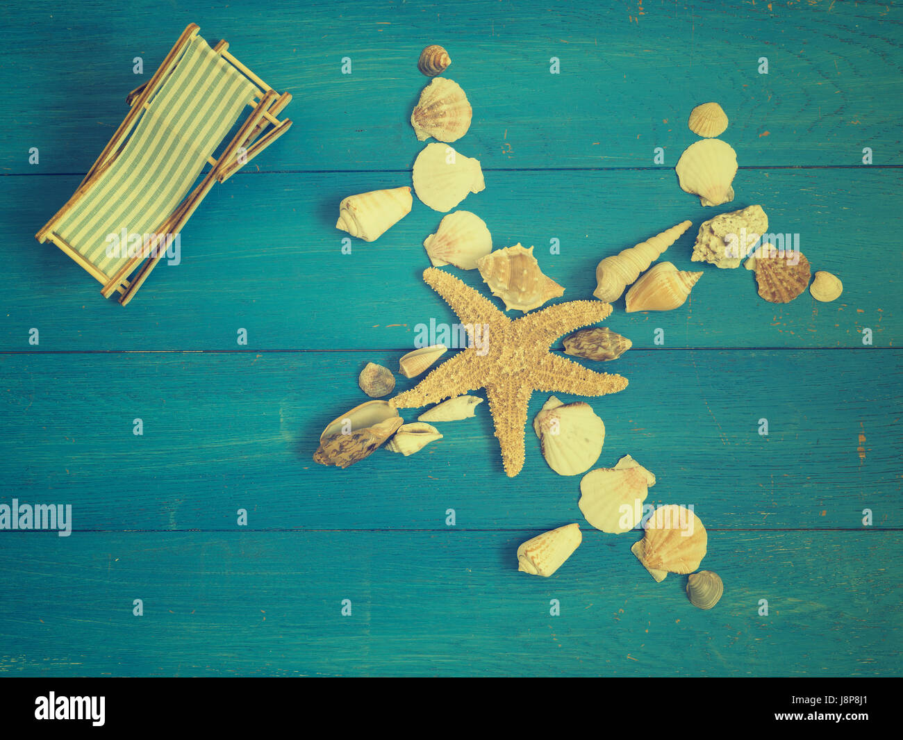 Airplane of seashells and starfish with a deckchair on a blue wooden ...
