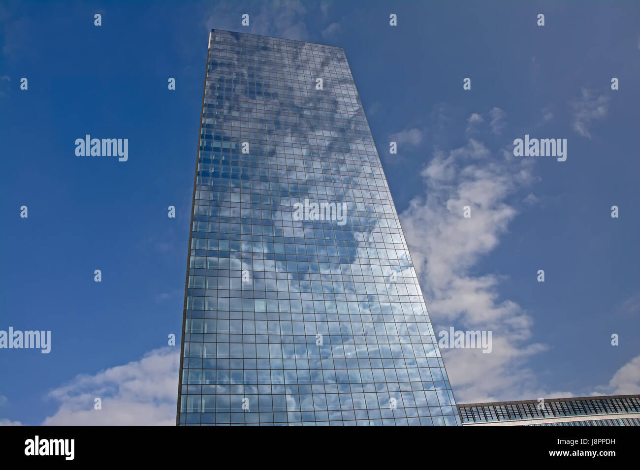 High rise office building with mirror windows reflecting blue sky and ...