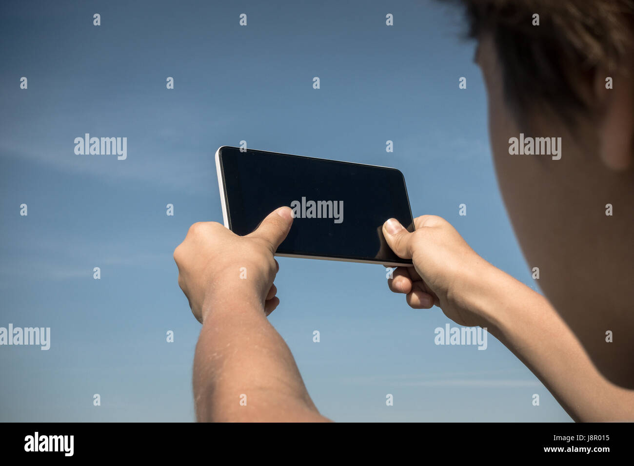 Boy taking photo with his smartphone. Back view. Close up Stock Photo ...