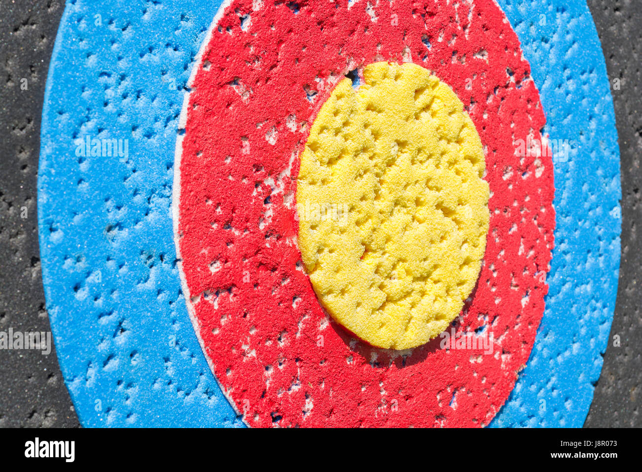 Well-used archery target with yellow bull's-eye, and numerous arrow ...