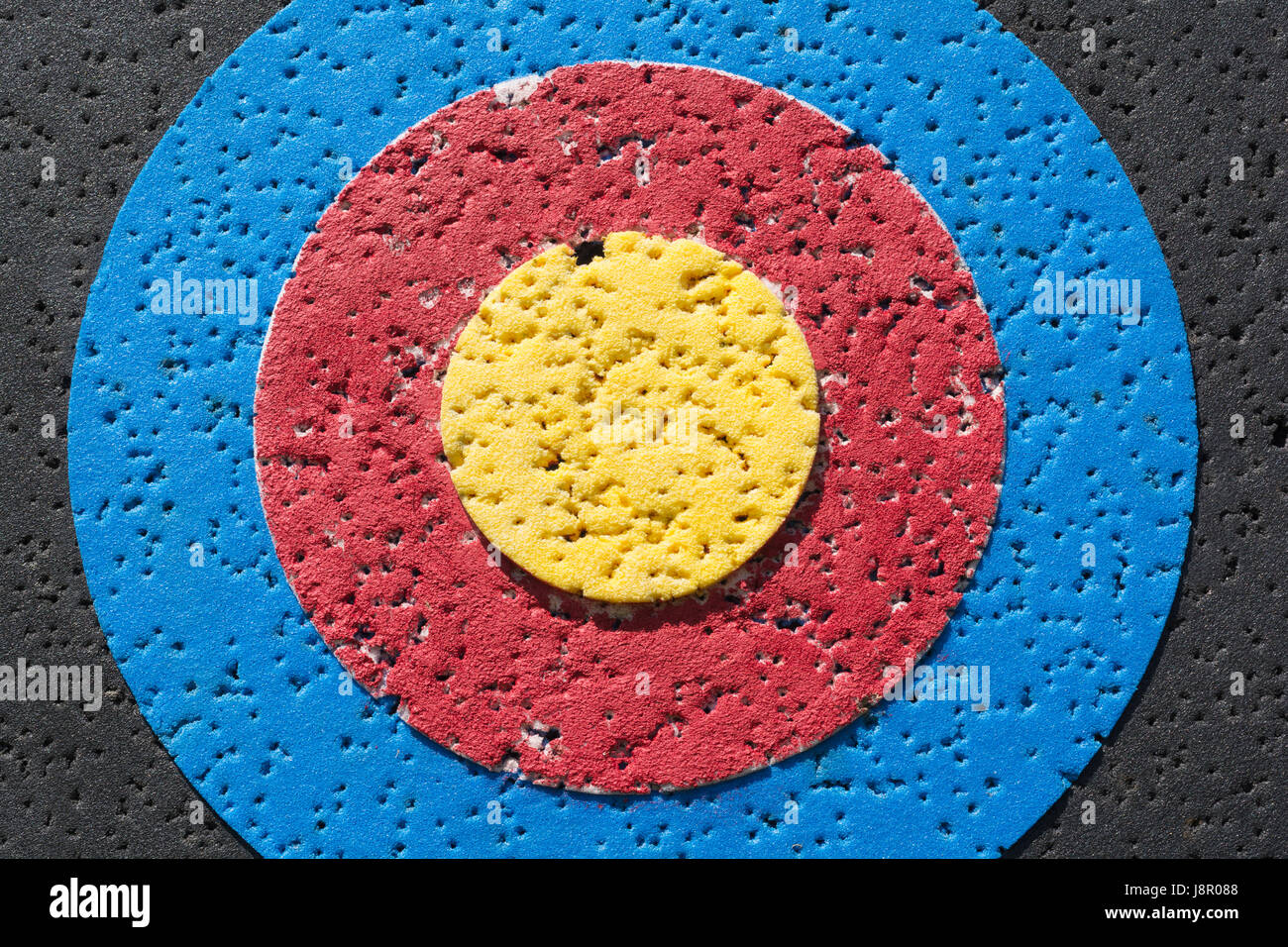 Well-used archery target with yellow bull's-eye, and numerous arrow ...