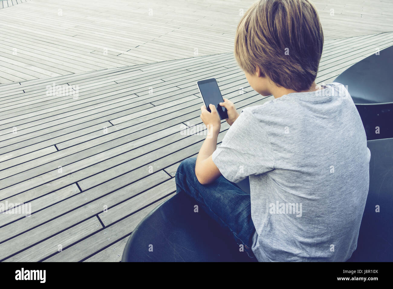 Boy with mobile phone. Back view Stock Photo - Alamy