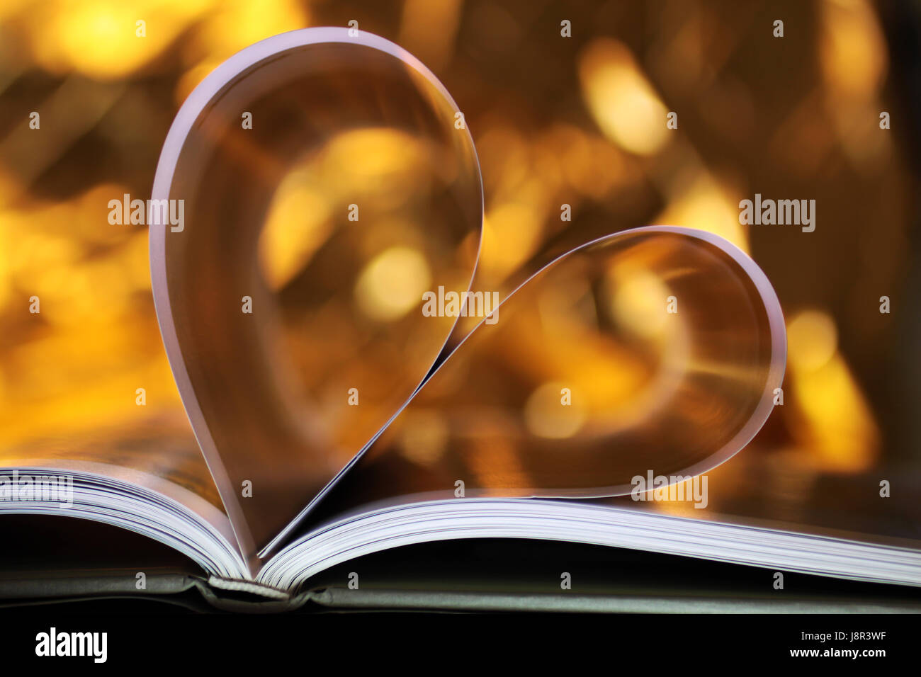 heart from book pages in front of golden background Stock Photo - Alamy