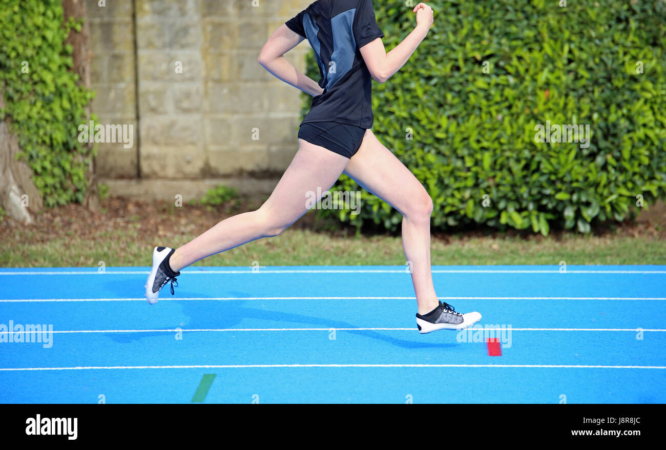 Young girl runs fast on the athletics track during sports training ...