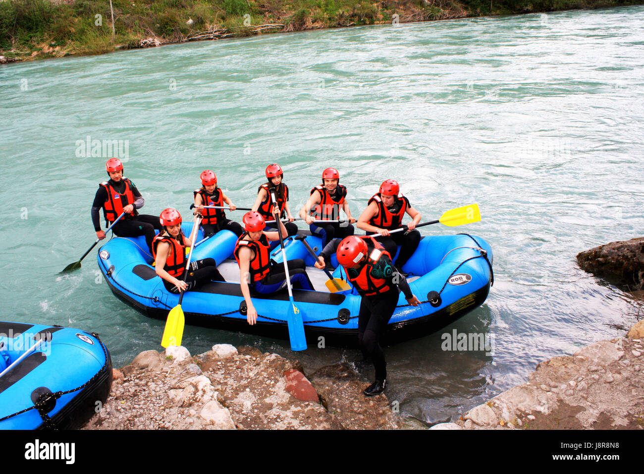 Group of happy people with guide whitewater rafting and rowing on river ...