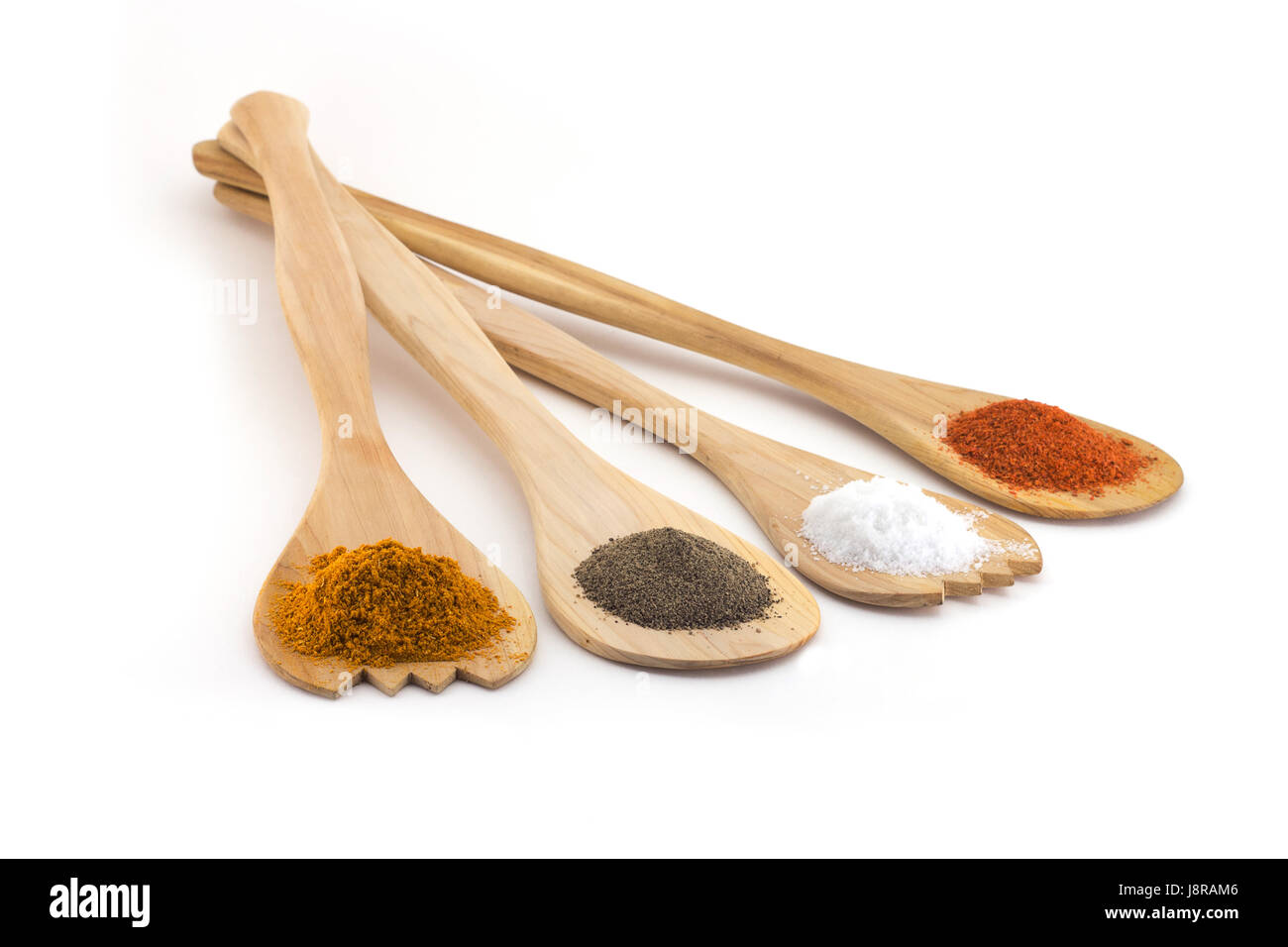 Four royal spices on wooden spoons, salt, black pepper, chilli pepper ...