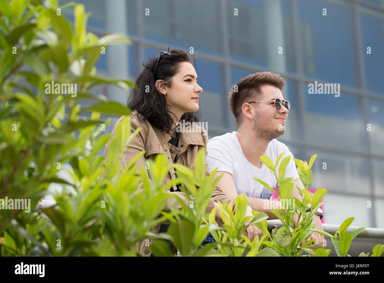 The two young people, a boy and a girl, standing, leaning against the ...