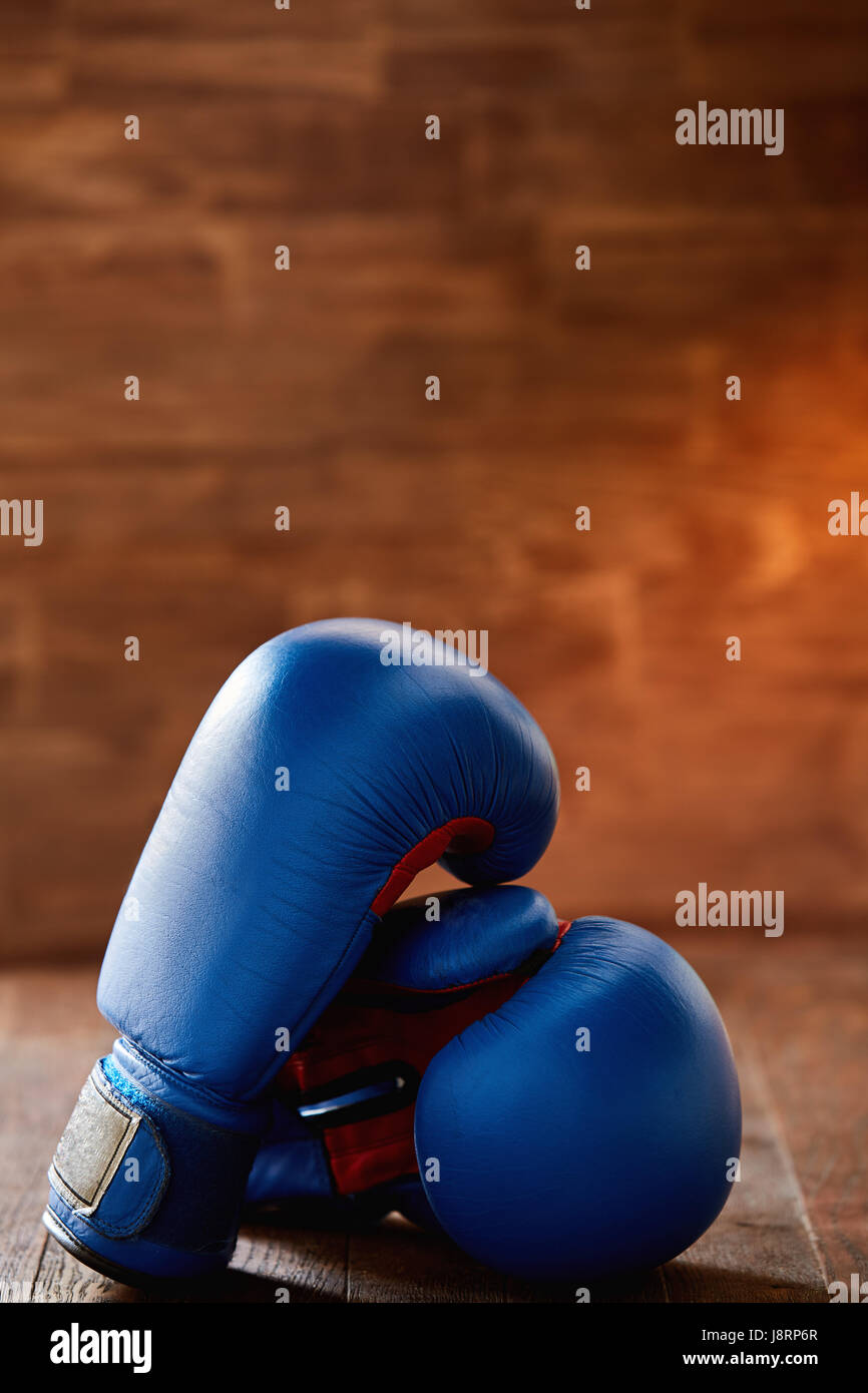 Pair of the two red boxing gloves lie on wooden table against wooden ...